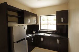 Uma cozinha moderna com armários pretos, uma geladeira de aço inoxidável e uma janela que oferece luz natural.