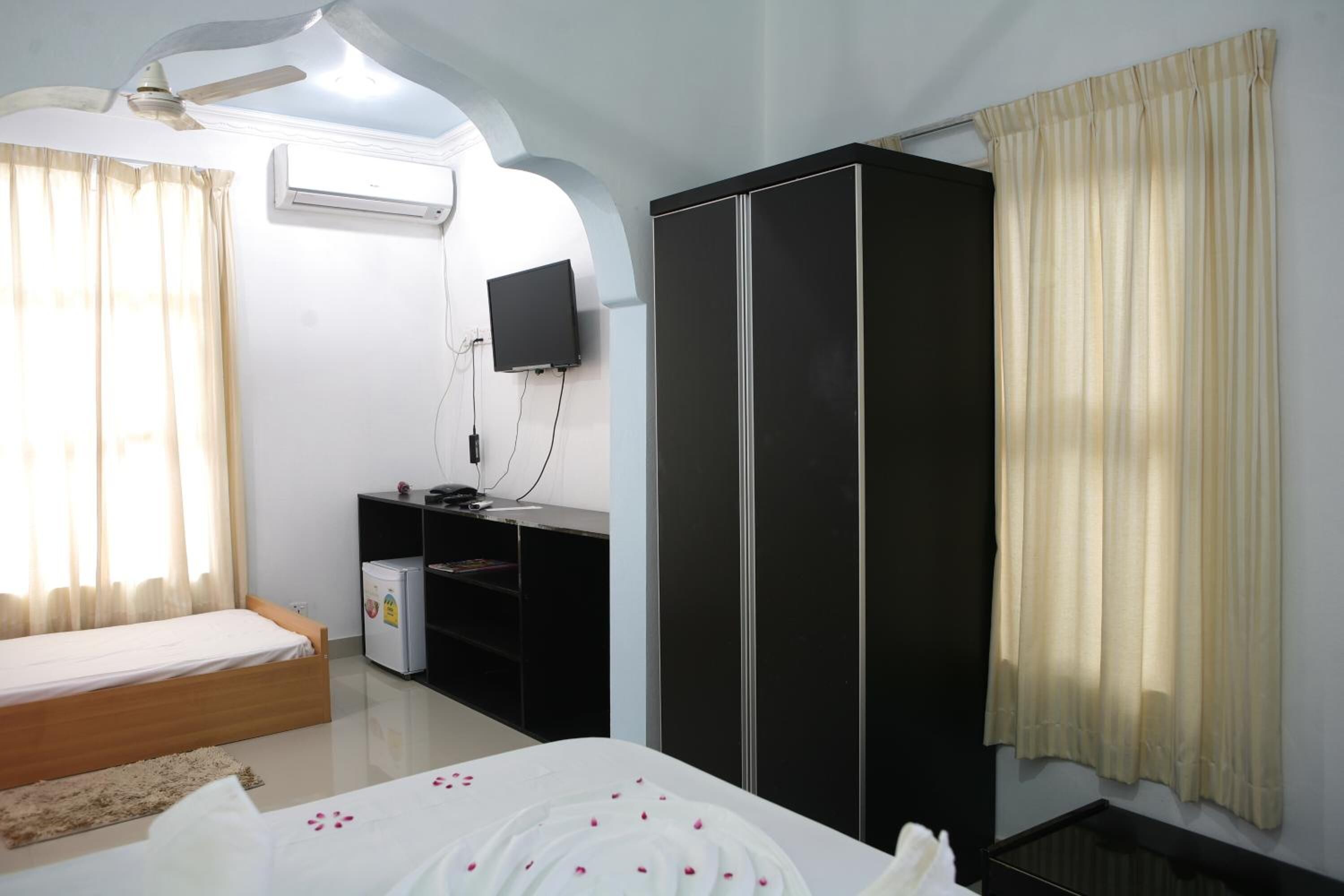 Quarto com cama, guarda-roupa, escrivaninha com computador e ar condicionado.