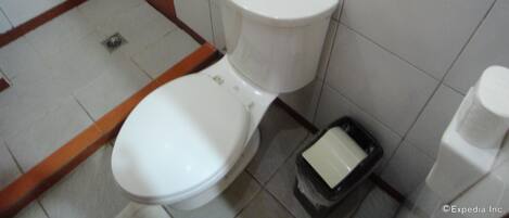 Casa de banho com sanita branca, bidé e um contentor de lixo.