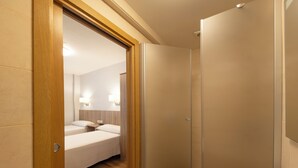 Quarto de hotel moderno com porta de madeira, cama, mesa de cabeceira e banheiro com banheira.