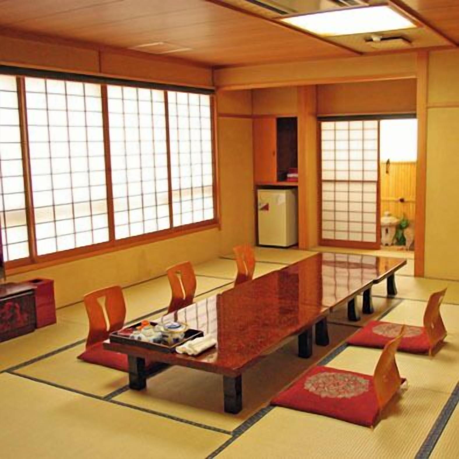 Um quarto em estilo tradicional japonês, com tatames, uma mesa baixa e portas deslizantes.
