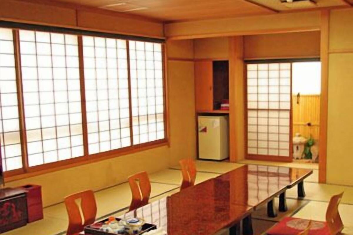 Um quarto em estilo tradicional japonês, com tatames, uma mesa baixa e portas deslizantes.