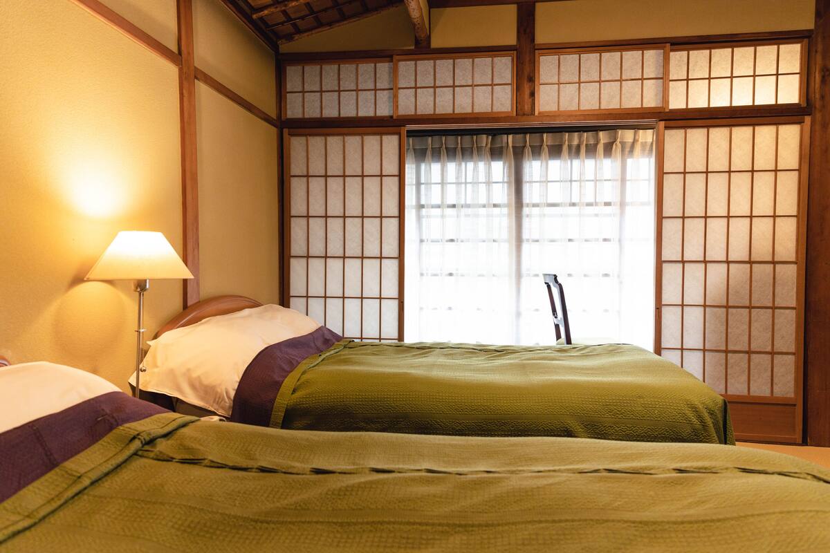Um quarto tradicional japonês com piso de tatame, um painel de shoji e uma cama com roupa de cama verde.