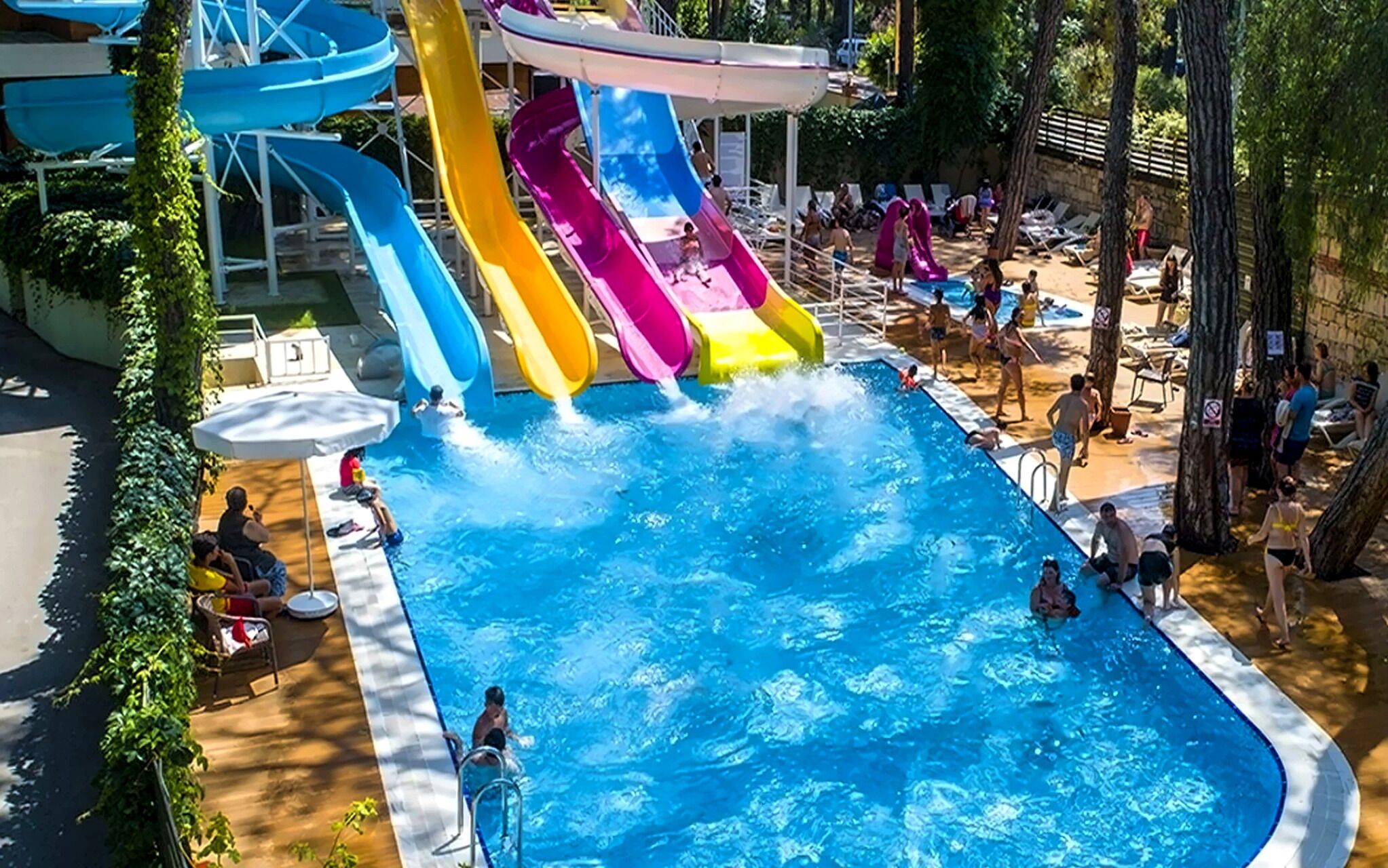 Piscina com vários toboáguas, rodeada por espreguiçadeiras e guarda-sóis.