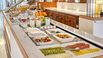 Buffet com diversos alimentos, incluindo frutas, carnes e laticínios.