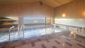 Uma piscina com vista para o mar, uma sauna e um banquinho de madeira.