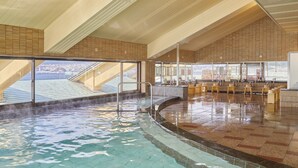 Piscina interior moderna com vista clara para o horizonte urbano através de amplas janelas.