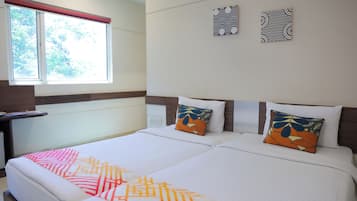 Quarto de hotel com uma cama grande, duas almofadas, uma mesa de cabeceira, uma janela e decoração na parede.