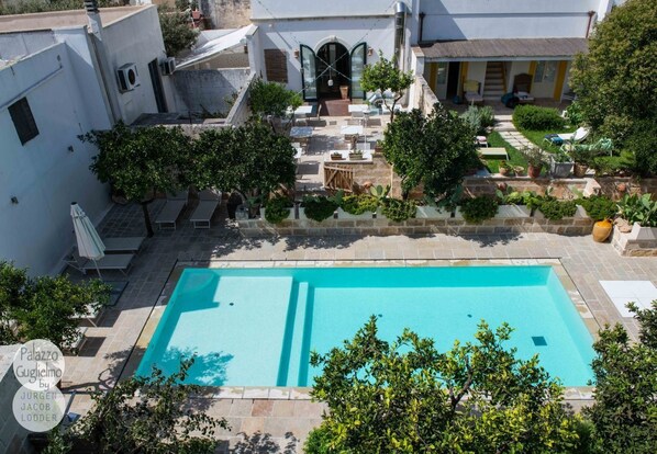 Piscina no terraço com vista desobstruída da arquitetura ao redor, incluindo uma escadaria que leva a uma entrada.