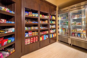 Um supermercado com prateleiras repletas de diversos produtos alimentares e uma área refrigerada.