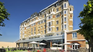 Um hotel com vários andares, com área de estar ao ar livre e gramado bem cuidado.
