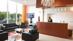 Uma área de recepção moderna com um balcão de madeira, sofás de couro preto e um grande candelabro.