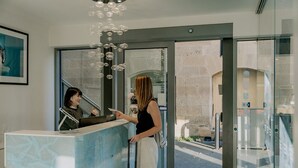 Uma área de recepção com balcão de mármore, um recepcionista e um hóspede.