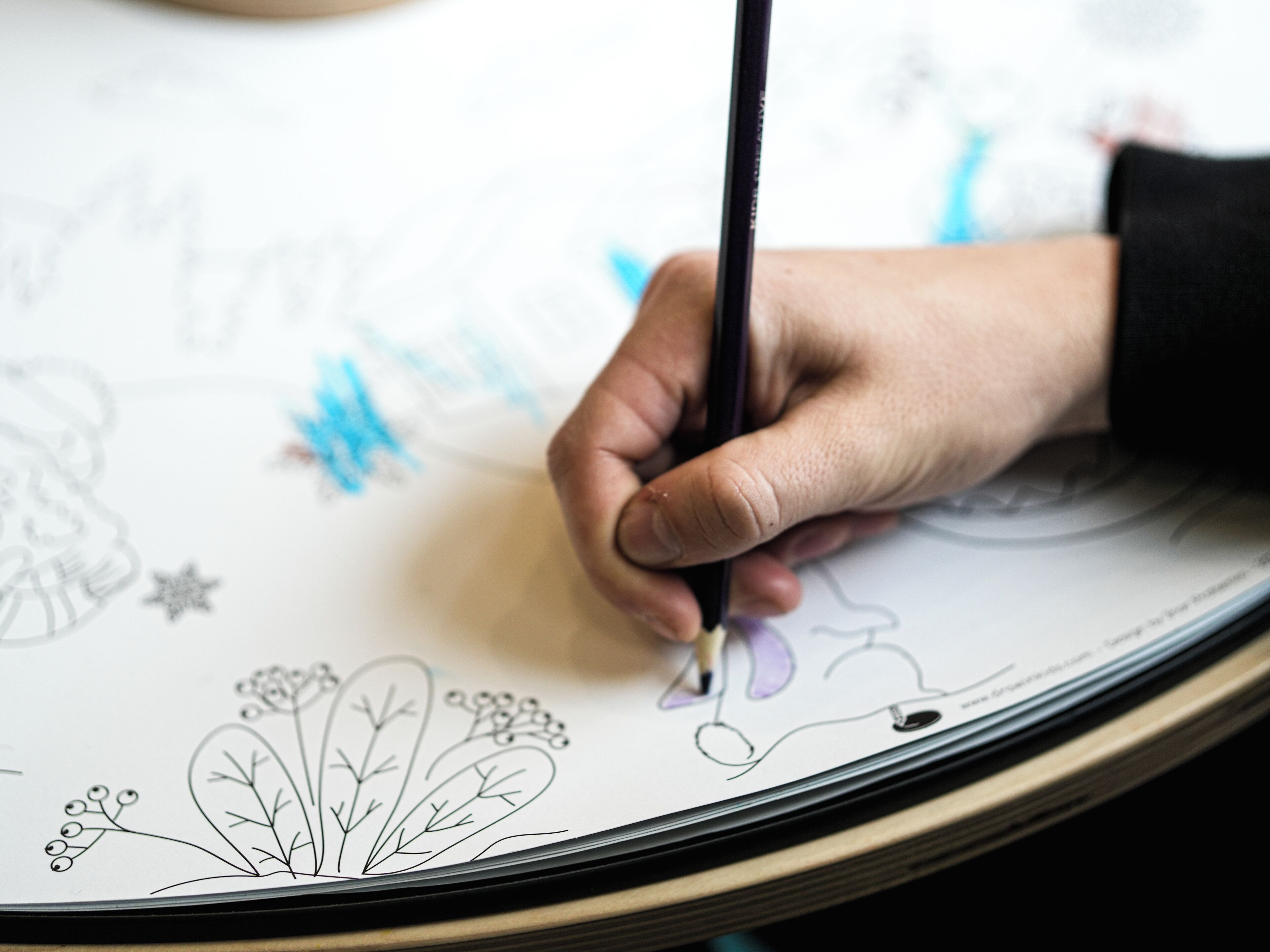 Uma mão colorindo um desenho em papel circular.