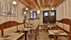 Um restaurante com assentos em camarotes de madeira e mesas, uma pintura grande na parede e luminárias pendentes.
