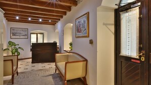 Um hall de hotel com teto de madeira, balcão de recepção, um sofá e uma porta com uma placa.