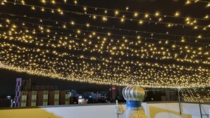 Terraço com luzes de Natal, uma pequena estrutura de recreação e um espelho d'água.