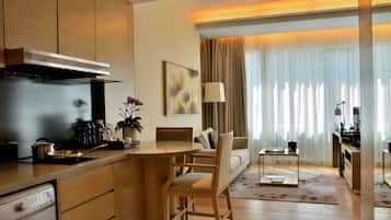 Quarto de hotel moderno com cozinha, mesa de jantar e sofá.