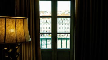 Quarto de hotel com vista para a paisagem urbana através de portas duplas.