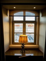 Uma lâmpada sobre uma mesa em frente a uma janela com vista para uma rua da cidade.