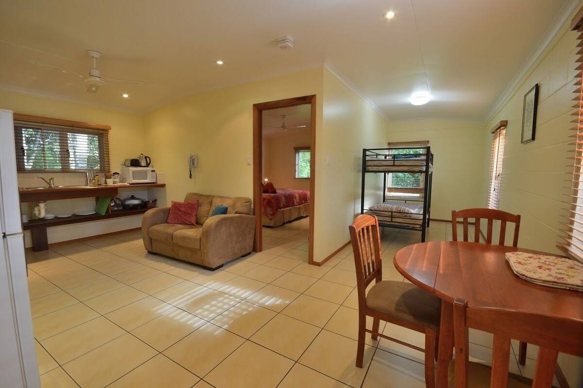 Um espaço compacto com cozinha compacta, sofá, mesa de jantar com cadeiras e uma cama beliche.