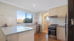 Cozinha moderna com uma ilha grande, eletrodomésticos de aço inoxidável e vista para o exterior.