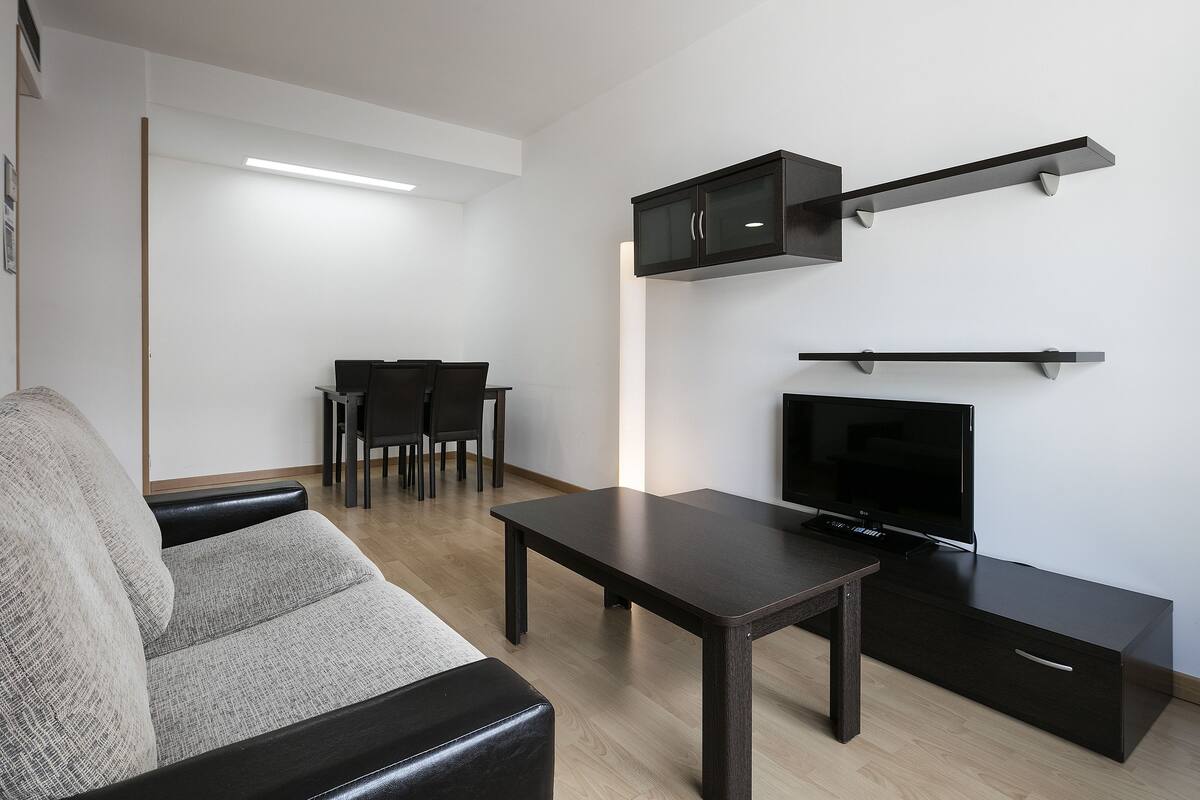 Uma sala de estar moderna com um sofá, uma mesa de centro, uma televisão e armários embutidos.