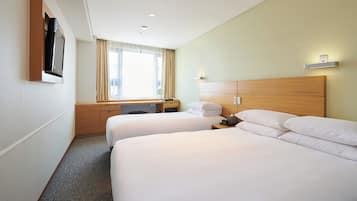 Quarto de hotel com duas camas, uma escrivaninha, televisão na parede e uma janela com cortinas.