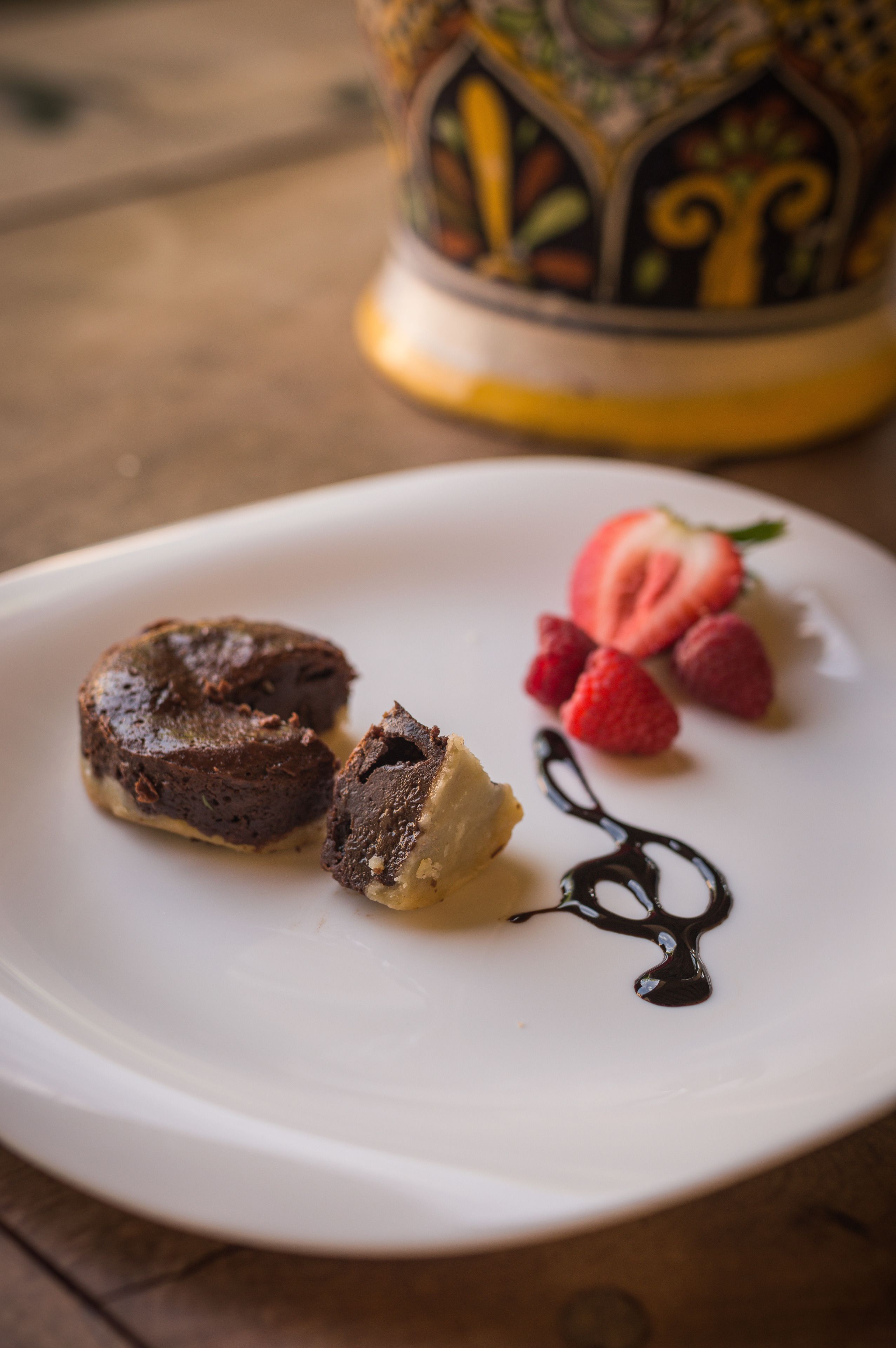 Prato de sobremesa com bolo de chocolate e morangos sobre um prato branco.