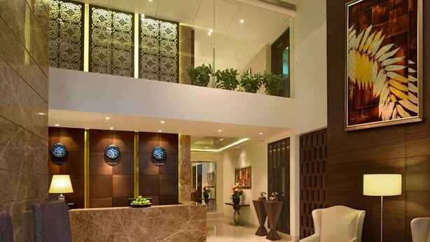 Um hall de entrada com balcão de recepção, área de estar e uma grande planta.