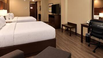 Quarto de hotel com duas camas, uma escrivaninha, uma cadeira, uma televisão e uma lixeira.