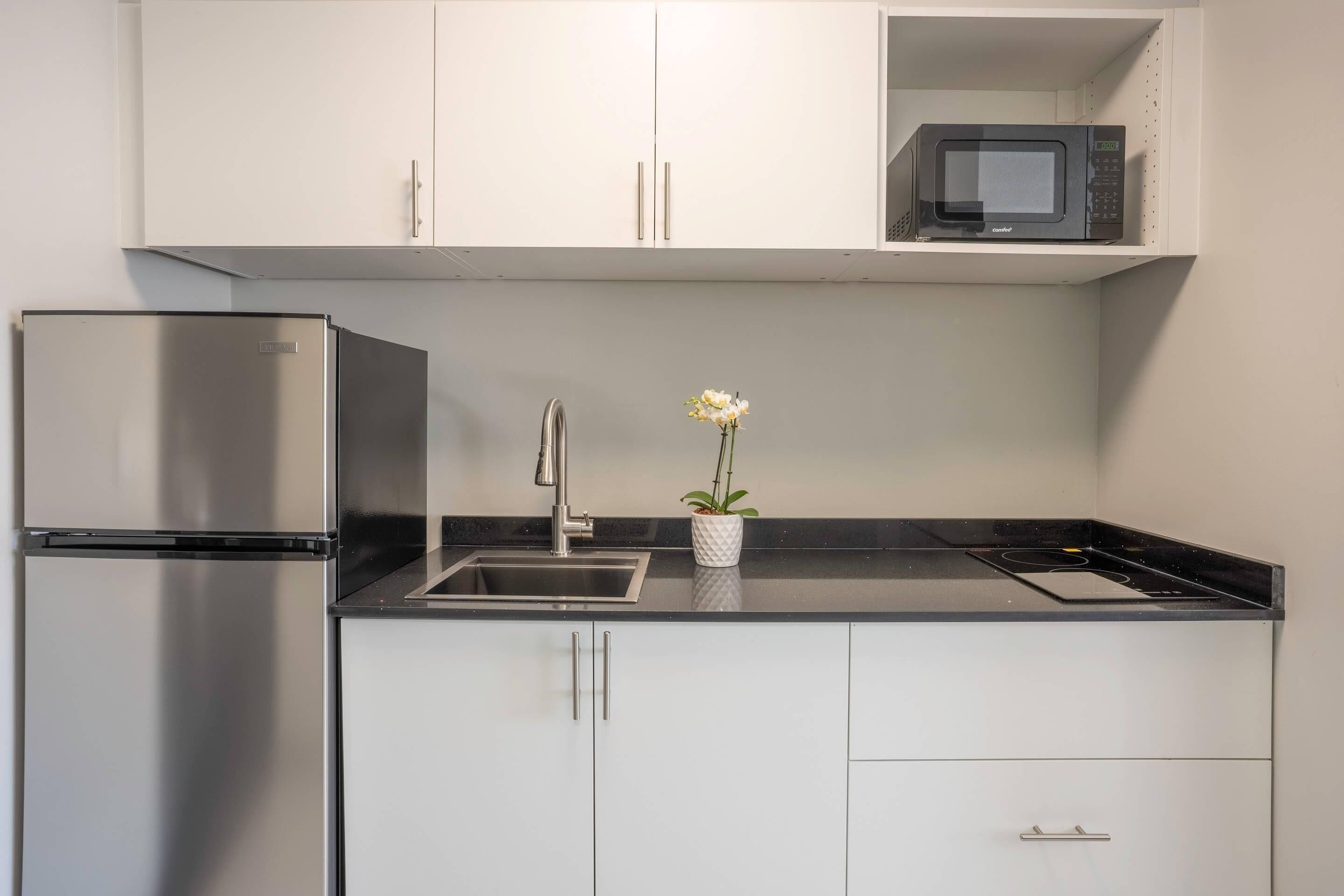 Uma cozinha moderna com eletrodomésticos de aço inoxidável, uma pia e um micro-ondas.