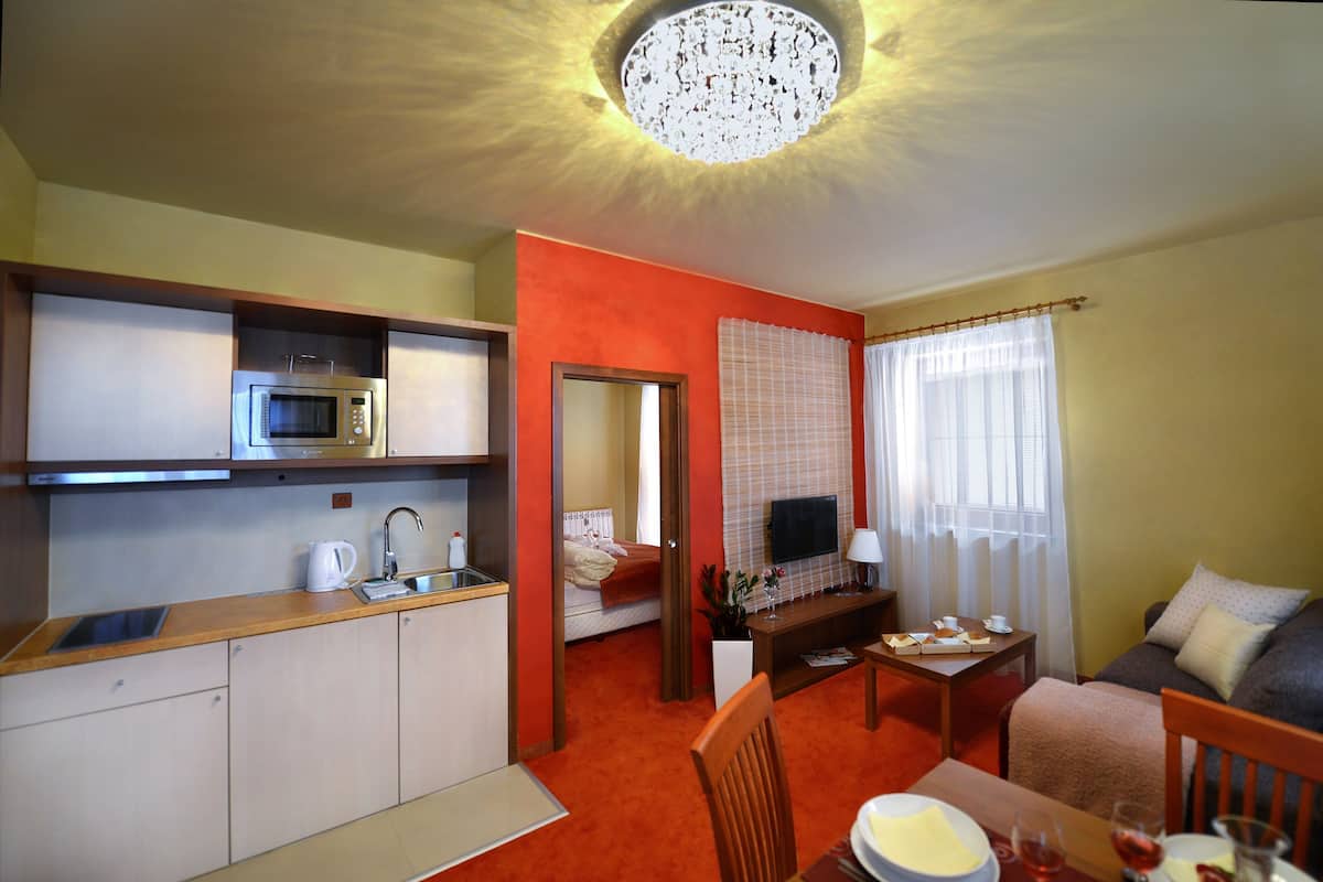 Quarto de hotel compacto com cozinha compacta, área de refeições, sofá e televisão.