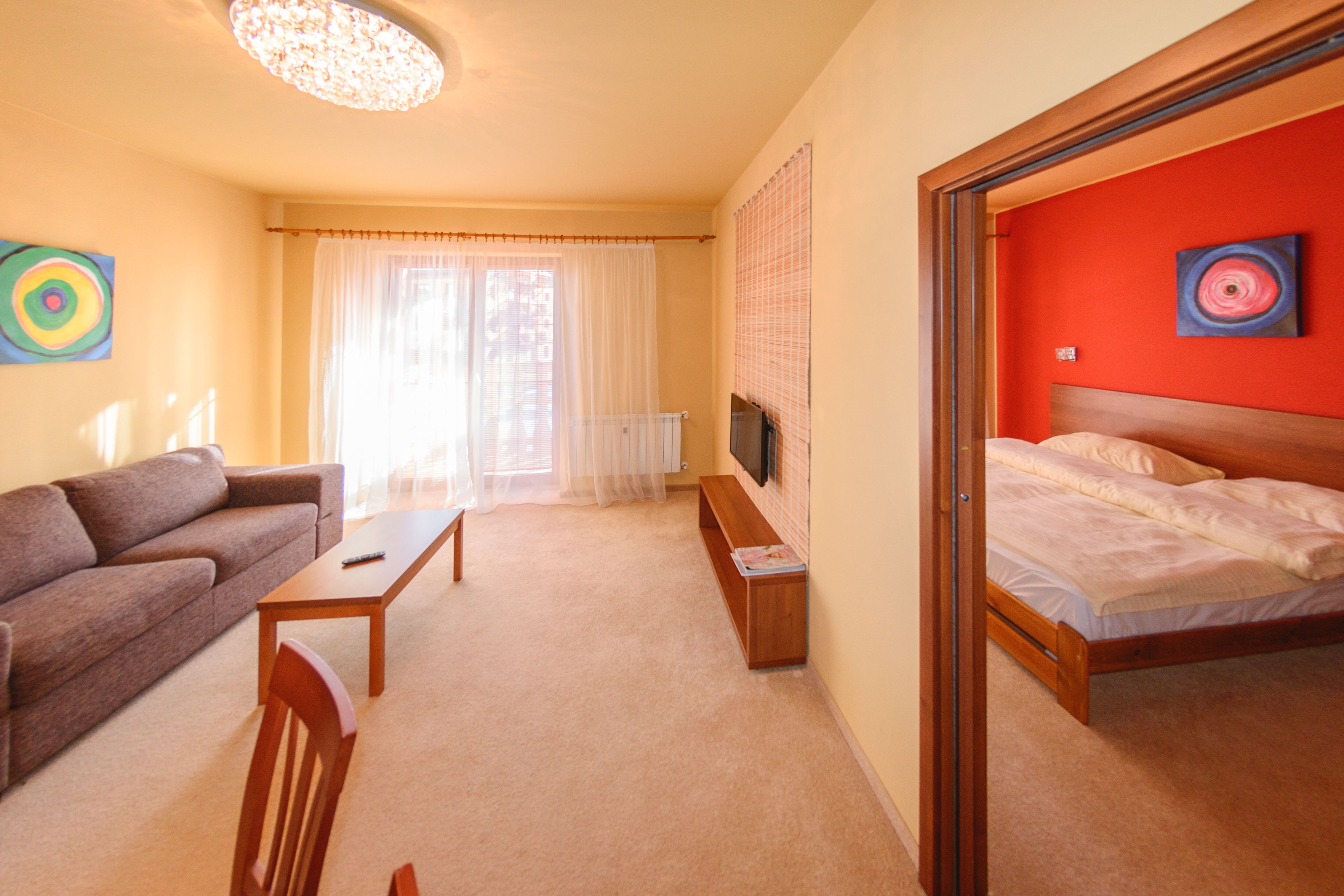 Quarto de hotel com sofá, mesa de madeira, cama e televisão.