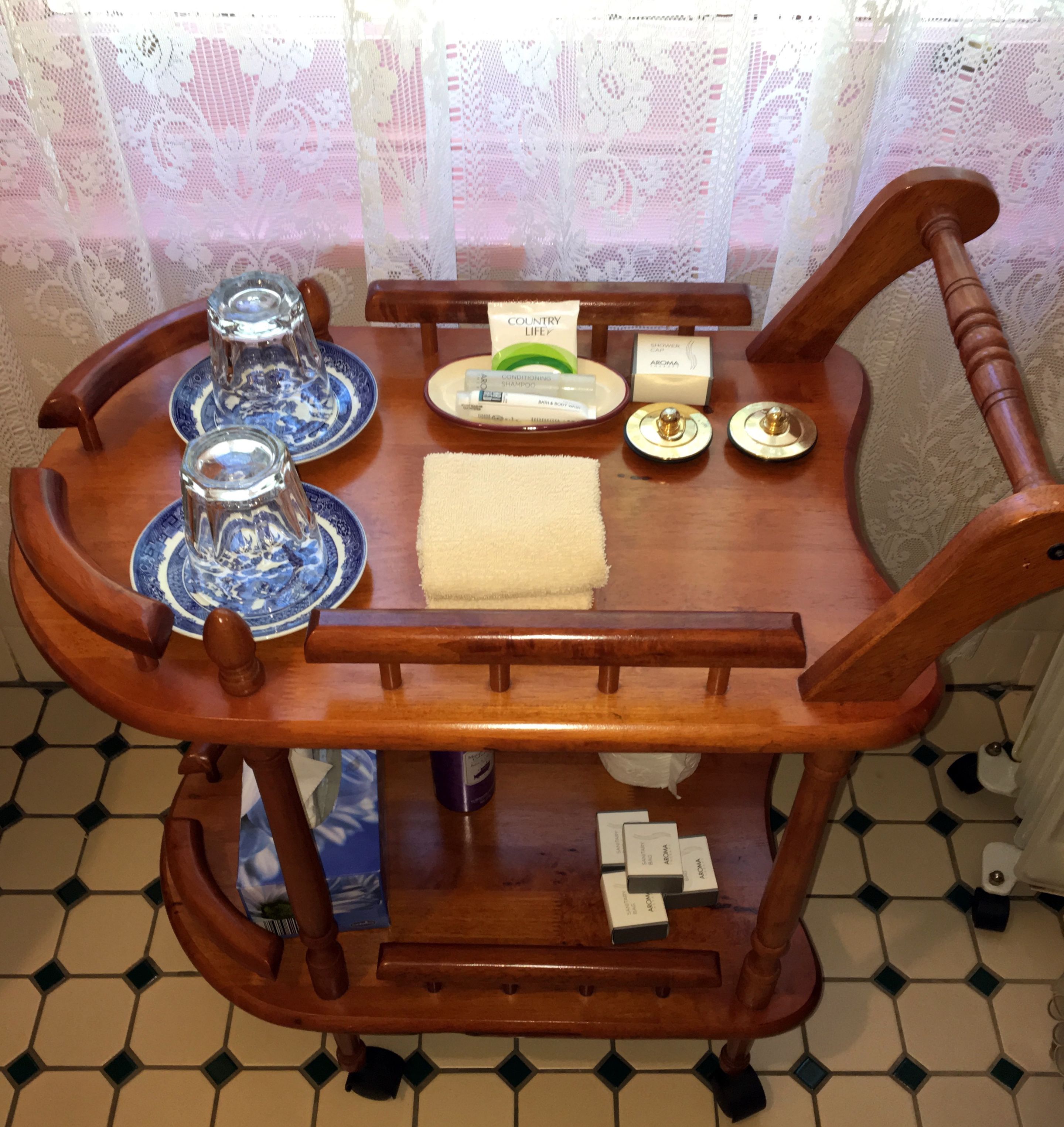Uma mesa de madeira com bandeja, dois copos, uma toalha e artigos de higiene.
