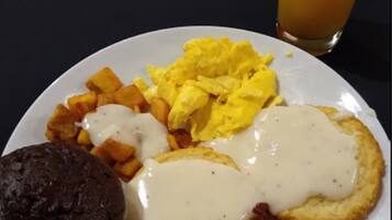 Um prato com ovos mexidos, bacon, um muffin e batatas palha.