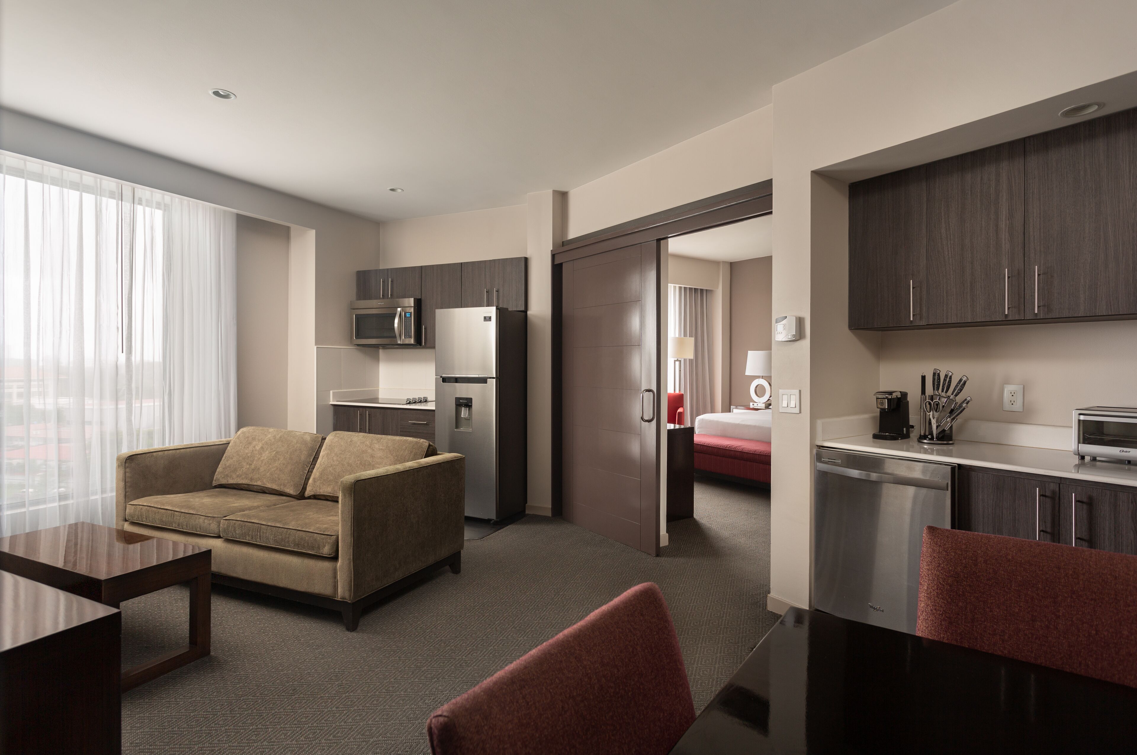 Quarto de hotel com sala de estar, cozinha compacta e quarto separado.
