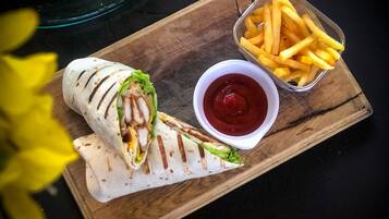 Um wrap com batatas fritas e ketchup sobre uma tábua de madeira.
