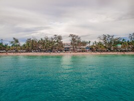 Na praia, areia branca, espreguiçadeiras, guarda-sóis 