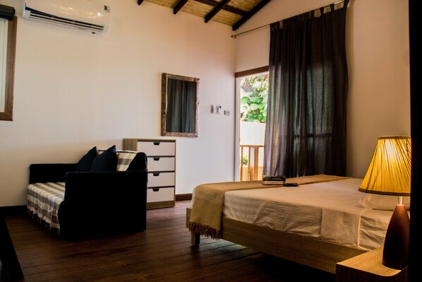 Um quarto com cama, sofá, cômoda e ar condicionado.