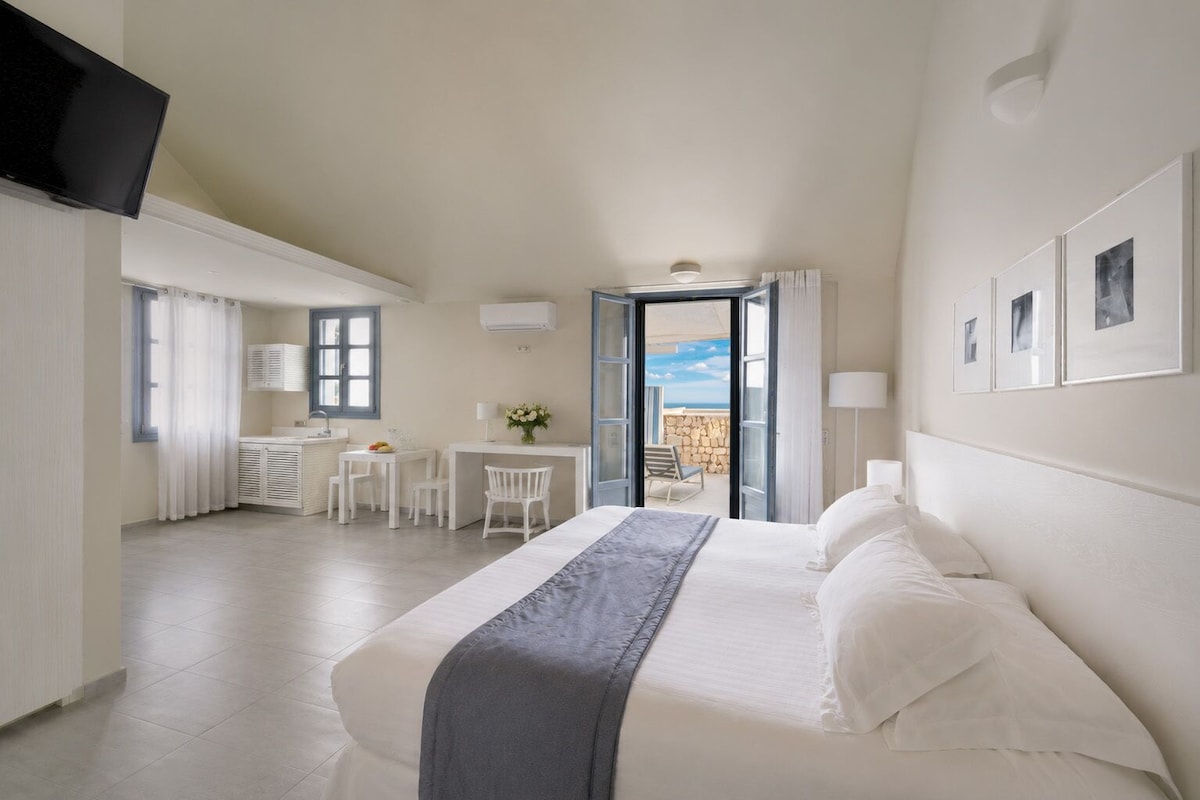 Quarto de hotel com cama, escrivaninha e vista para o exterior.