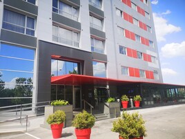 Um edifício moderno com toldo vermelho, grandes janelas e plantas em vasos na frente.