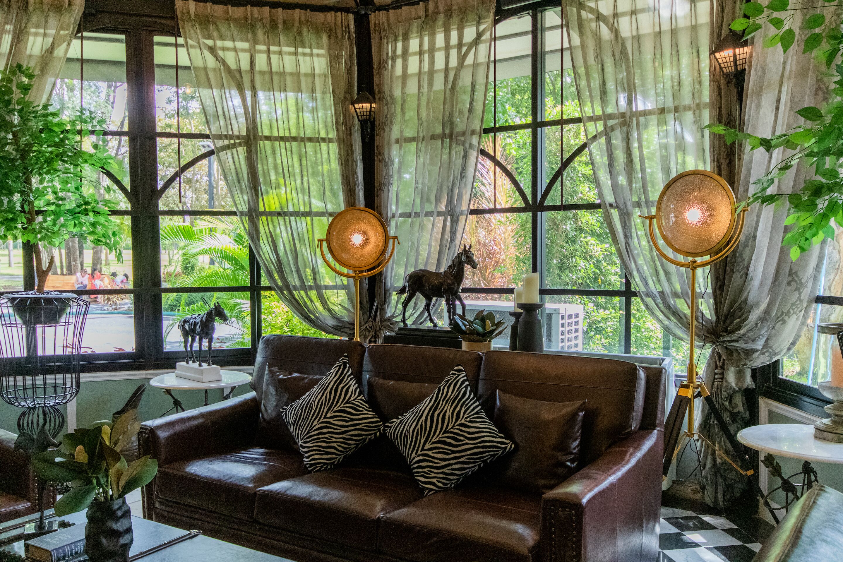 Um quarto acolhedor com um sofá de couro, almofadas estampadas com padrão de zebra e uma estátua de um cavalo.