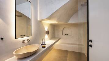 Casa de banho moderna com uma grande pia oval, espelho independente e chuveiro integrado, com design minimalista.