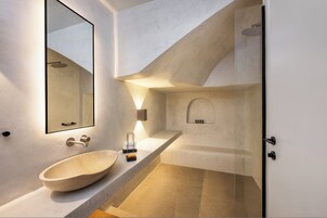 Casa de banho moderna com uma grande pia oval, espelho independente e chuveiro integrado, com design minimalista.