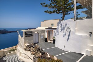 Um edifício branco com uma escadaria de pedra que leva a um terraço com vista para o mar.