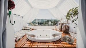 Uma banheira de hidromassagem em uma sala coberta com vista para uma encosta.