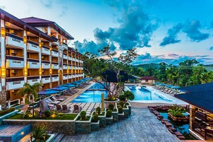 Um hotel com vários andares, piscina e áreas de estar ao ar livre.