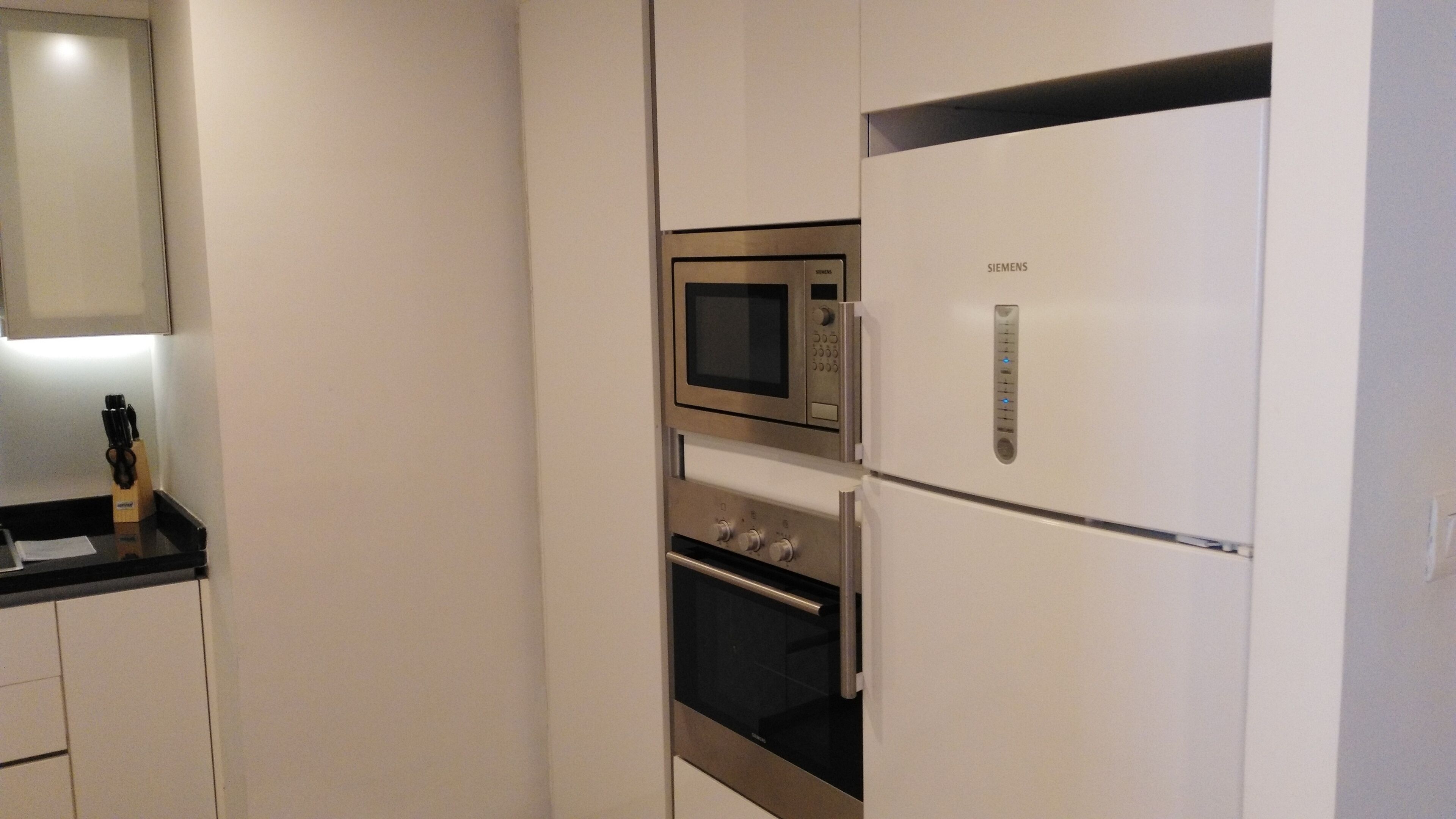 Uma cozinha compacta com micro-ondas, forno e frigorífico embutidos.