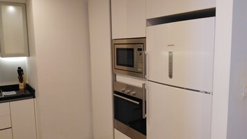 Uma cozinha compacta com micro-ondas, forno e frigorífico embutidos.